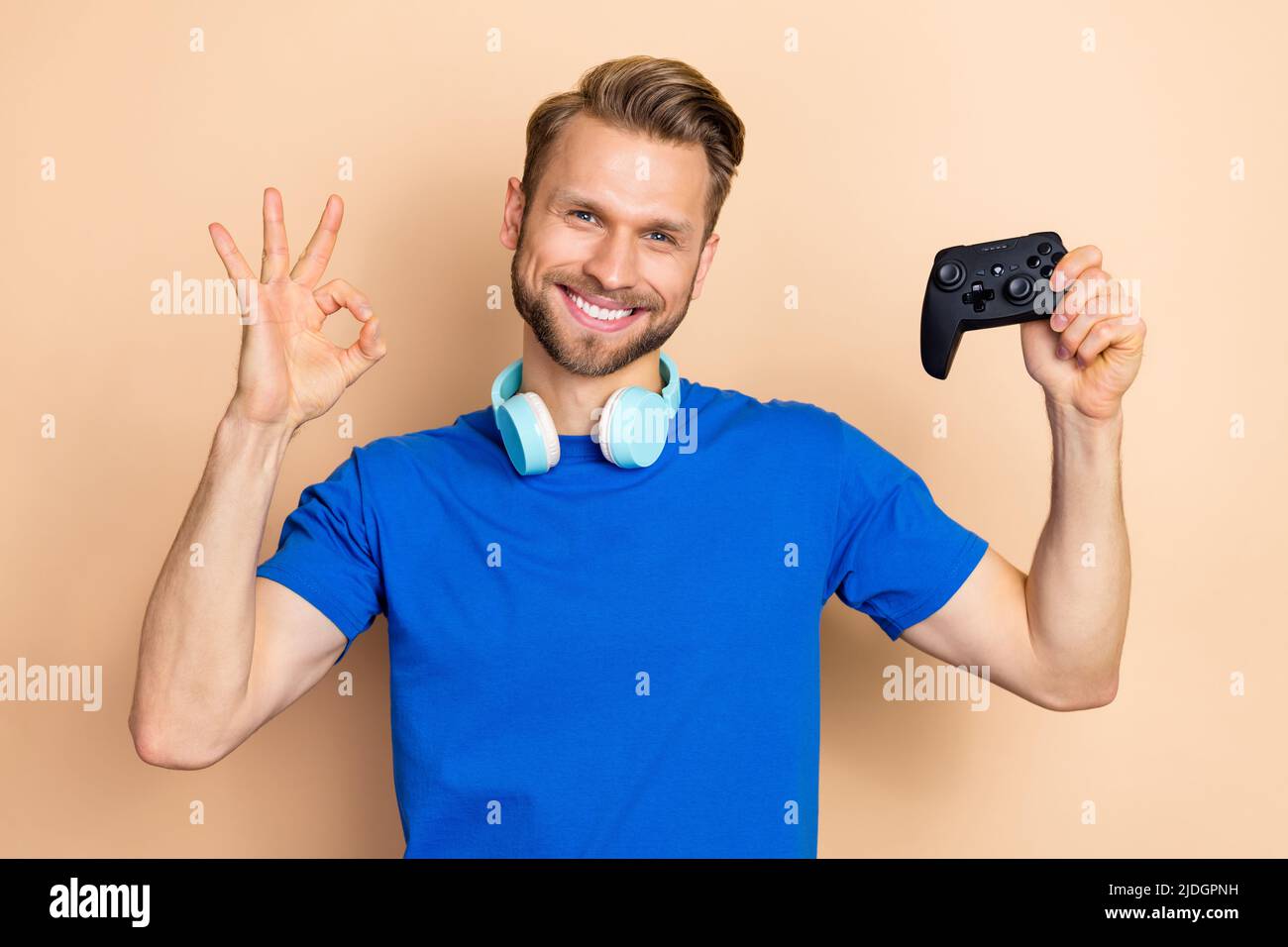 Photo of handsome positive man hold controller hand fingers show okey ...