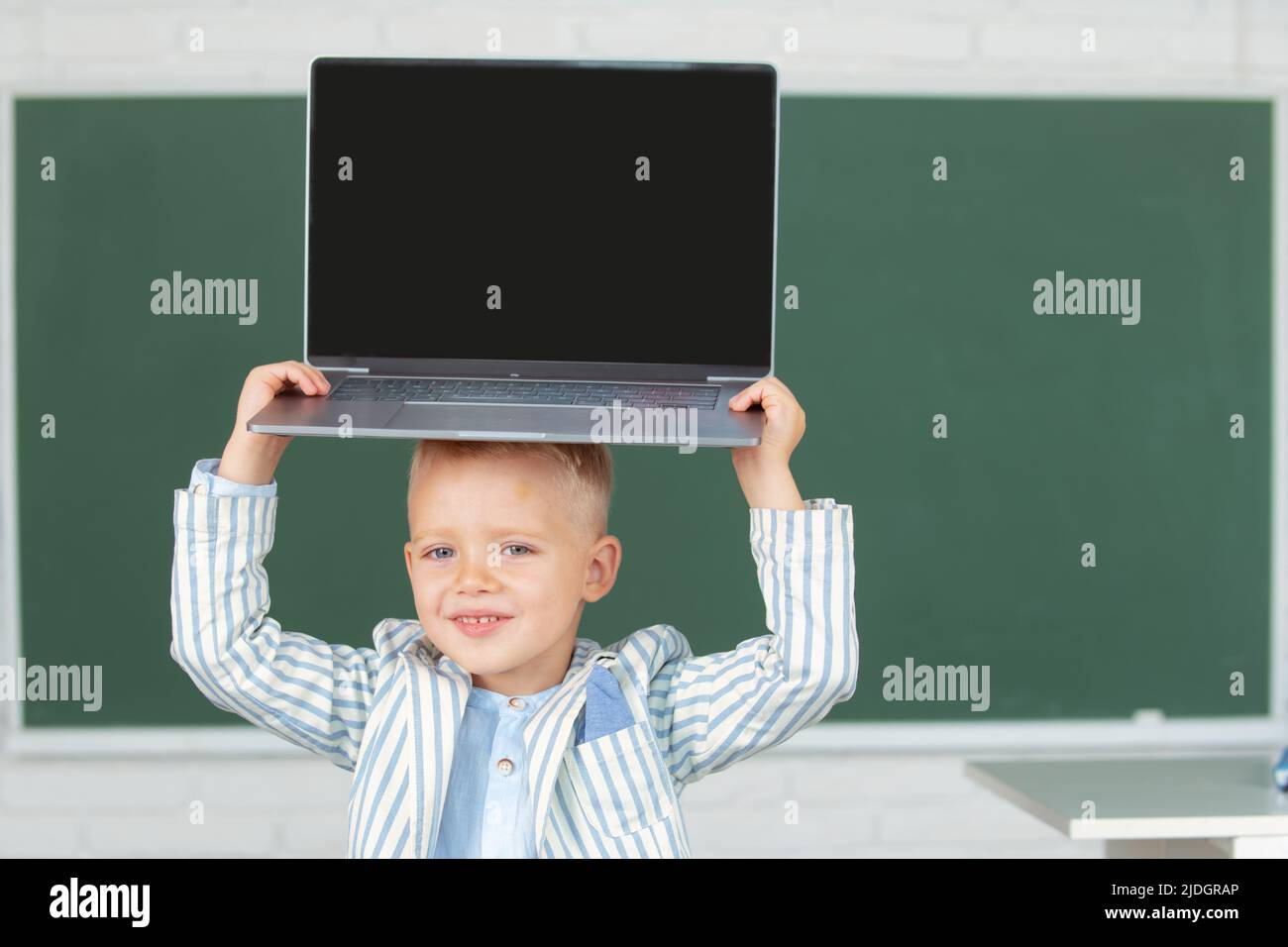 Cute little child using laptop computer, kid boy holding laptop on head ...