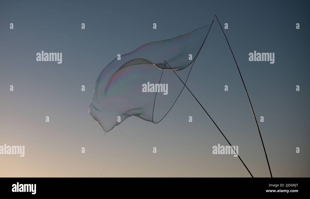 Big bubble flying over blue sky. Huge colorful soap bubbles fly over ...