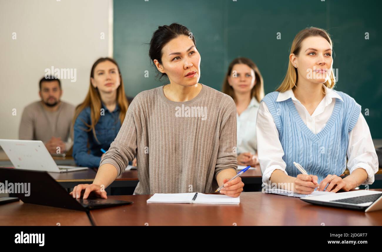 Group of adult students sitting at tables in classroom Stock Photo - Alamy