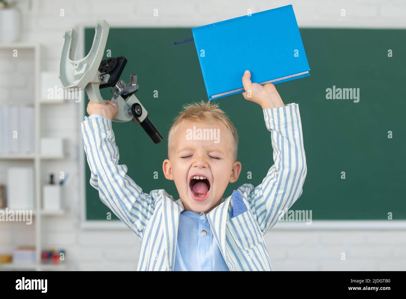 Back to school. Excited schoolboy pupil with microscope and book. Funny ...