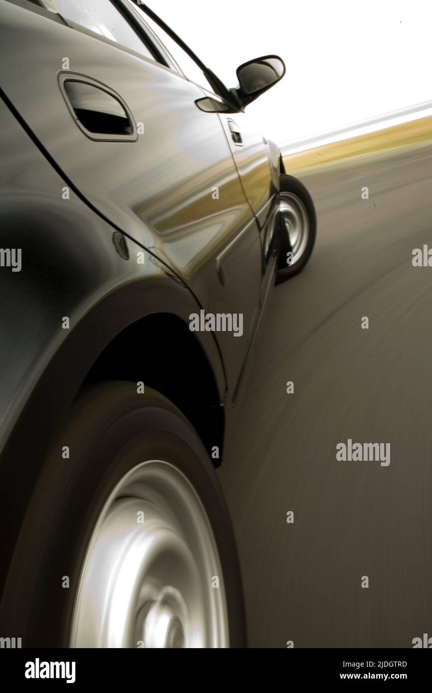 Black car turning sharply to its right, showing speed in tracking blur ...