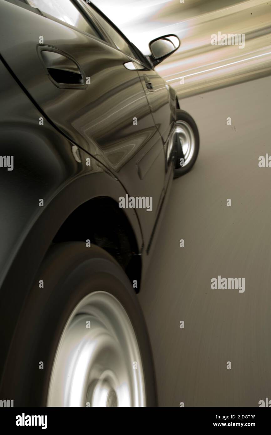 Black car turning sharply to its right, showing speed in tracking blur ...