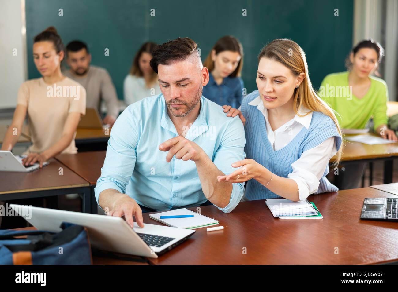 Woman and man university students using laptop and exercising together ...