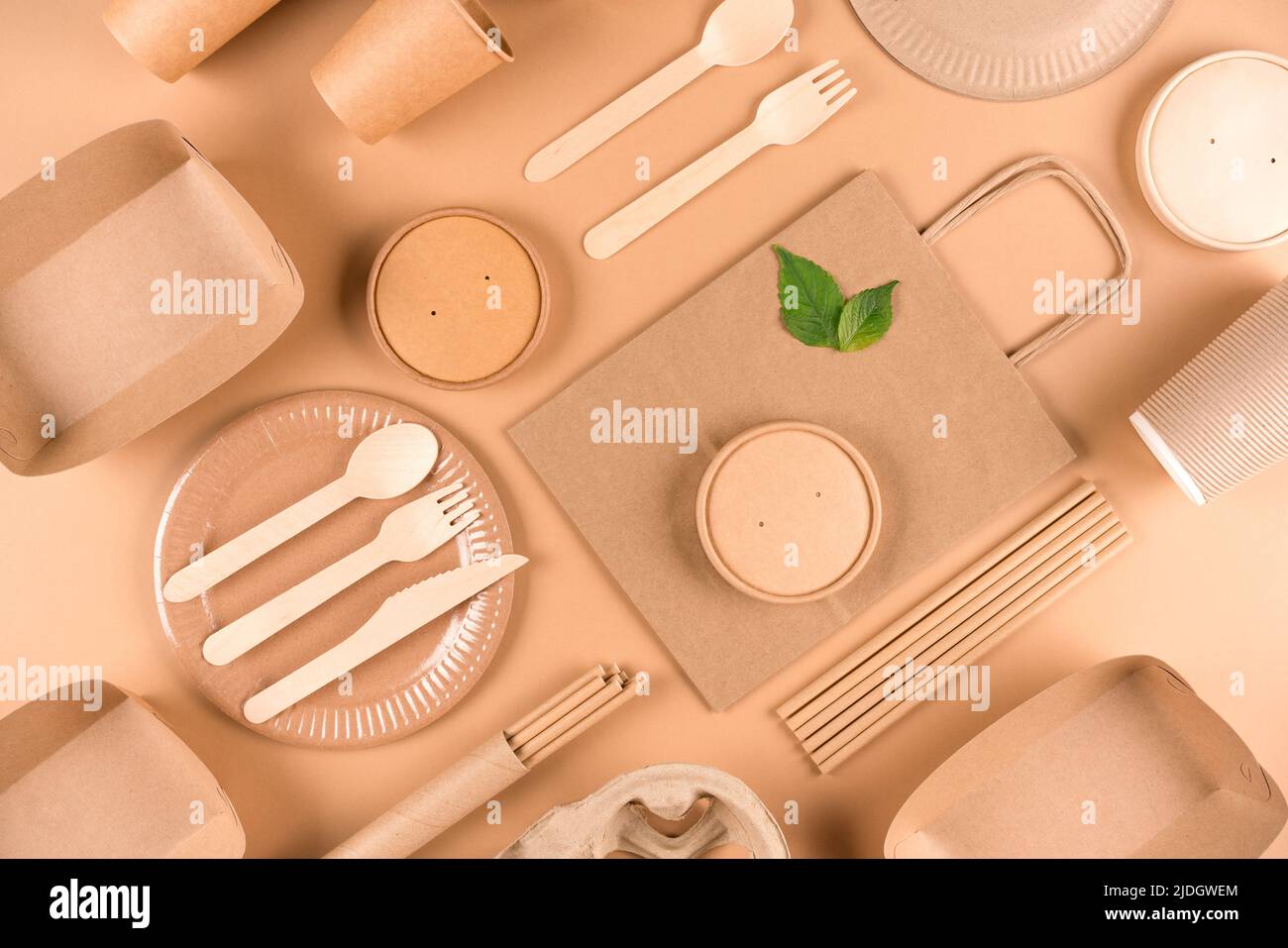 Paper utensils and wooden cutlery set over light brown background ...