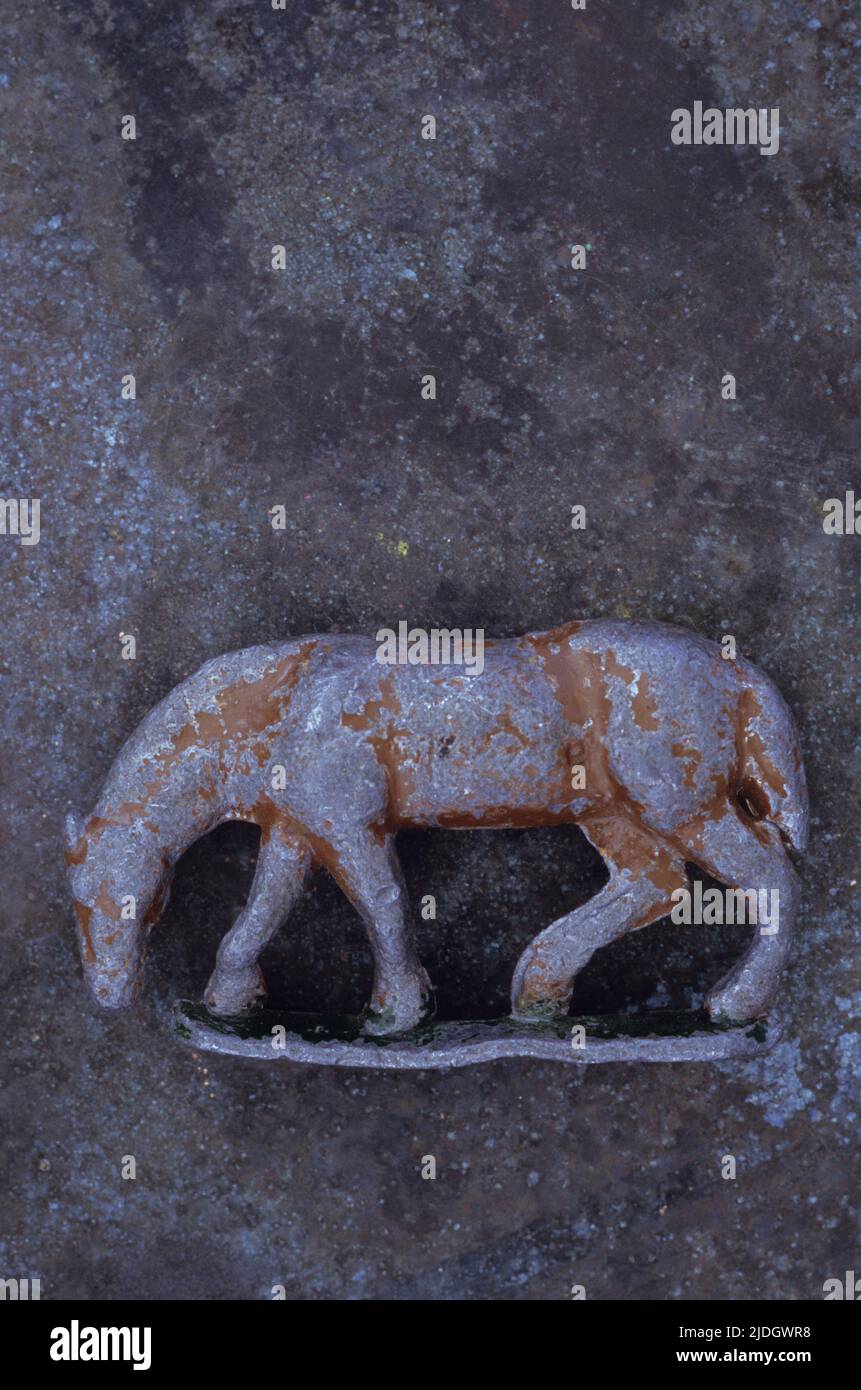 Battered lead model of grazing horse lying on tarnished metal Stock ...