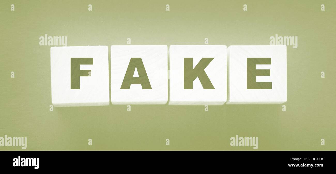 FAKE word written in wooden blocks on black background Stock Photo - Alamy