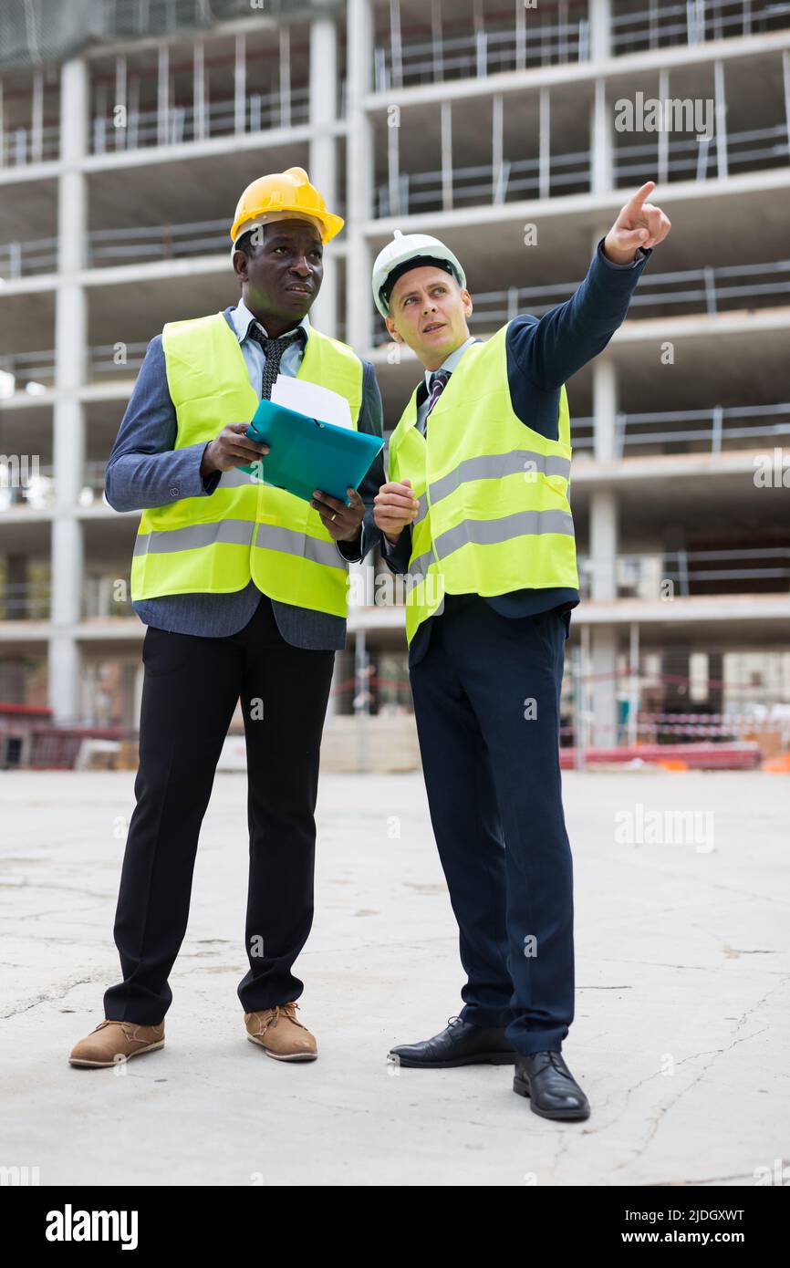 Young civil engineer discussing a construction plan with a colleague ...