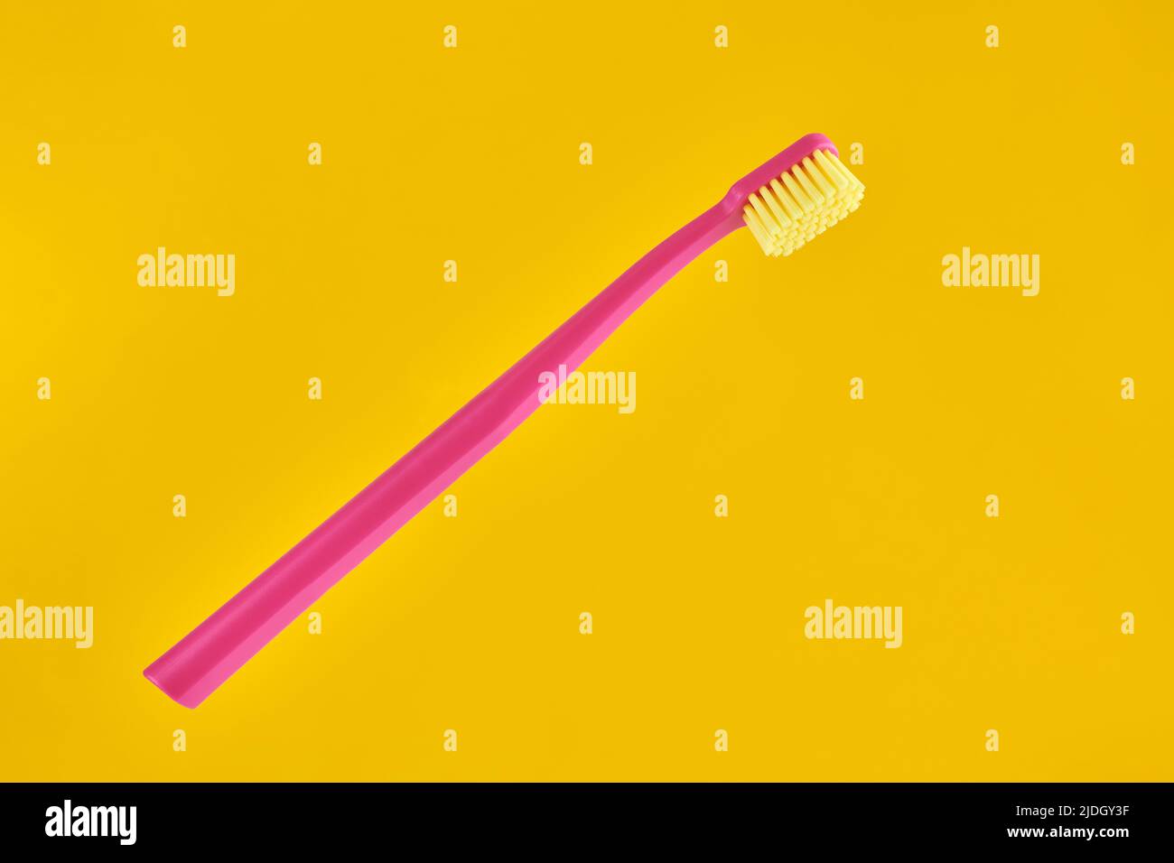 Pink toothbrush on yellow background for oral hygiene to clean teeth ...