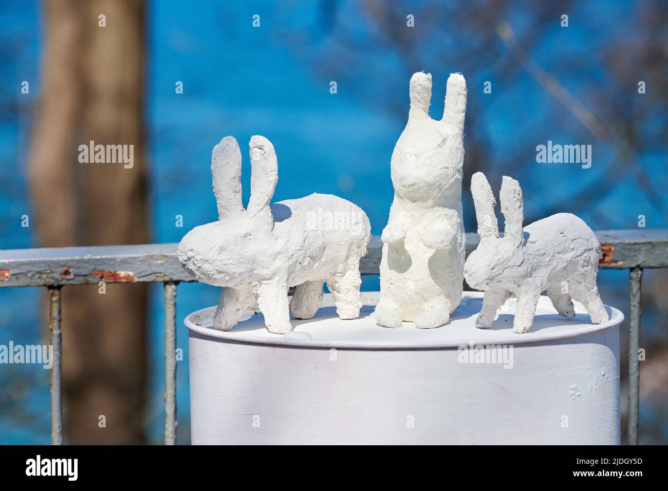 Three white rabbit statues made of plaster on barrel at outdoor art ...