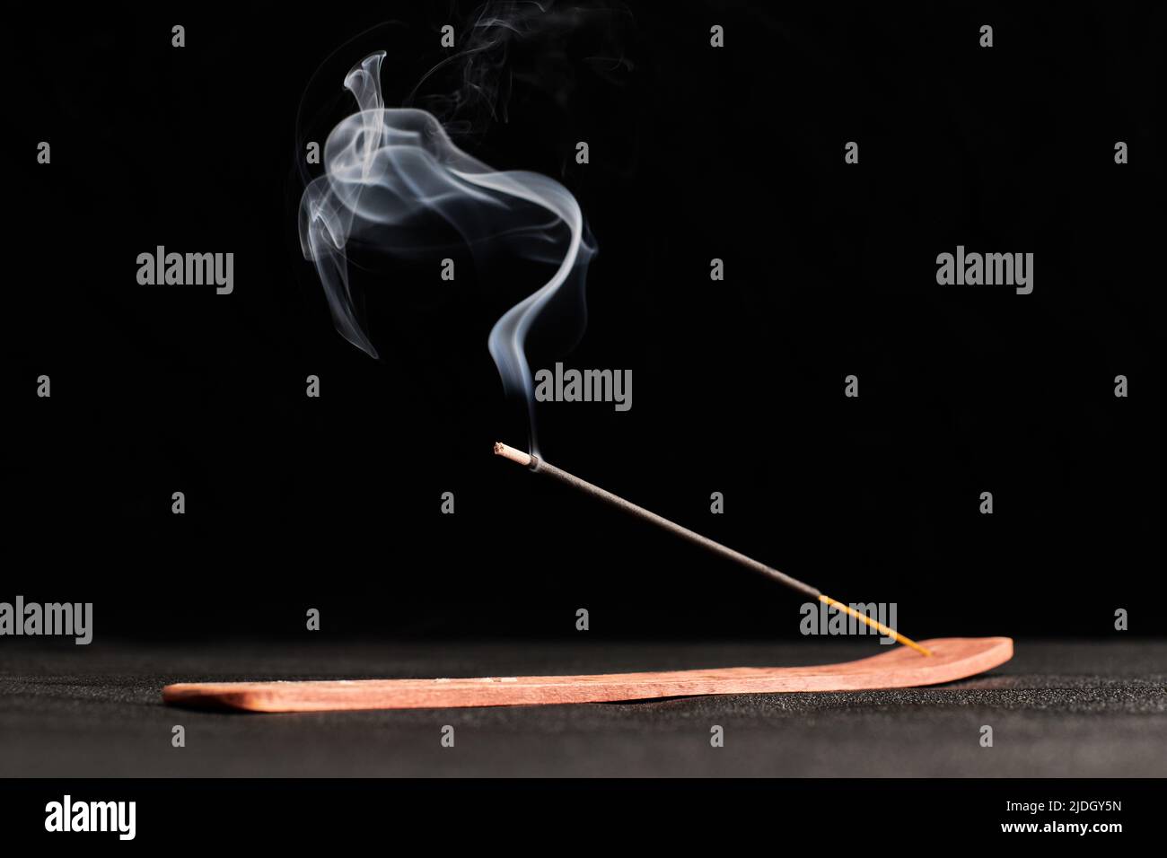 Smoke curls of incense stick in wooden holder for relaxation and ...