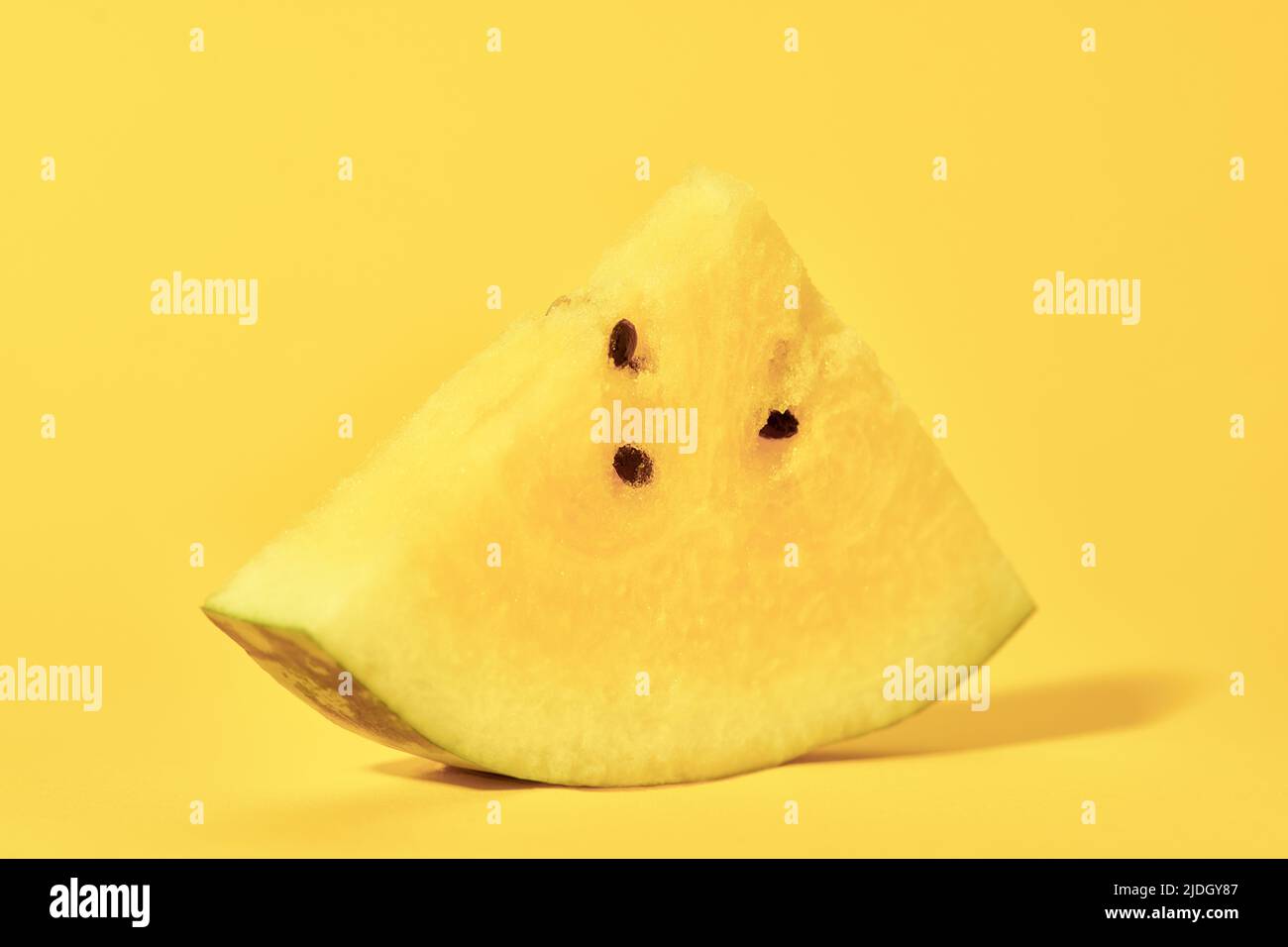 One piece of yellow watermelon with seeds on yellow background ...