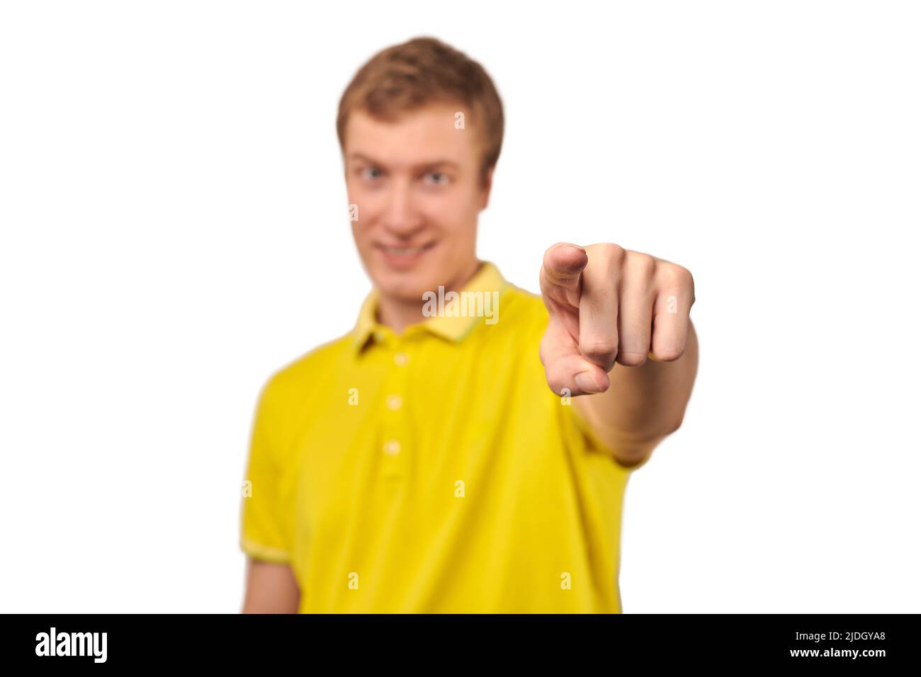 Smiling attractive guy in casual yellow T-shirt pointing finger forward ...