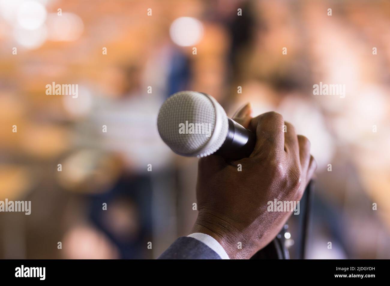 Male hand holding microphone at conference hall Stock Photo - Alamy
