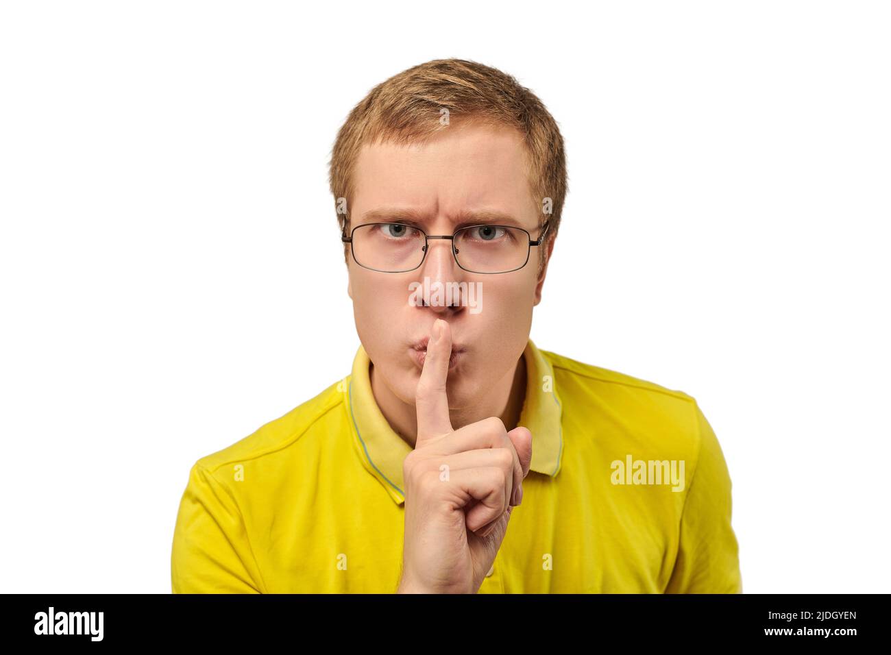 Funny young man in yellow T-shirt asking to be quiet, silence gesture ...