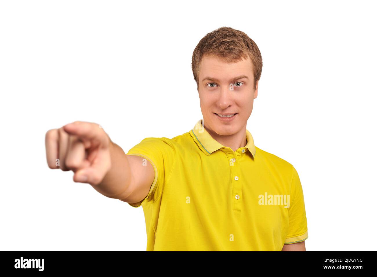 Smiling attractive guy in casual yellow T-shirt pointing finger forward ...
