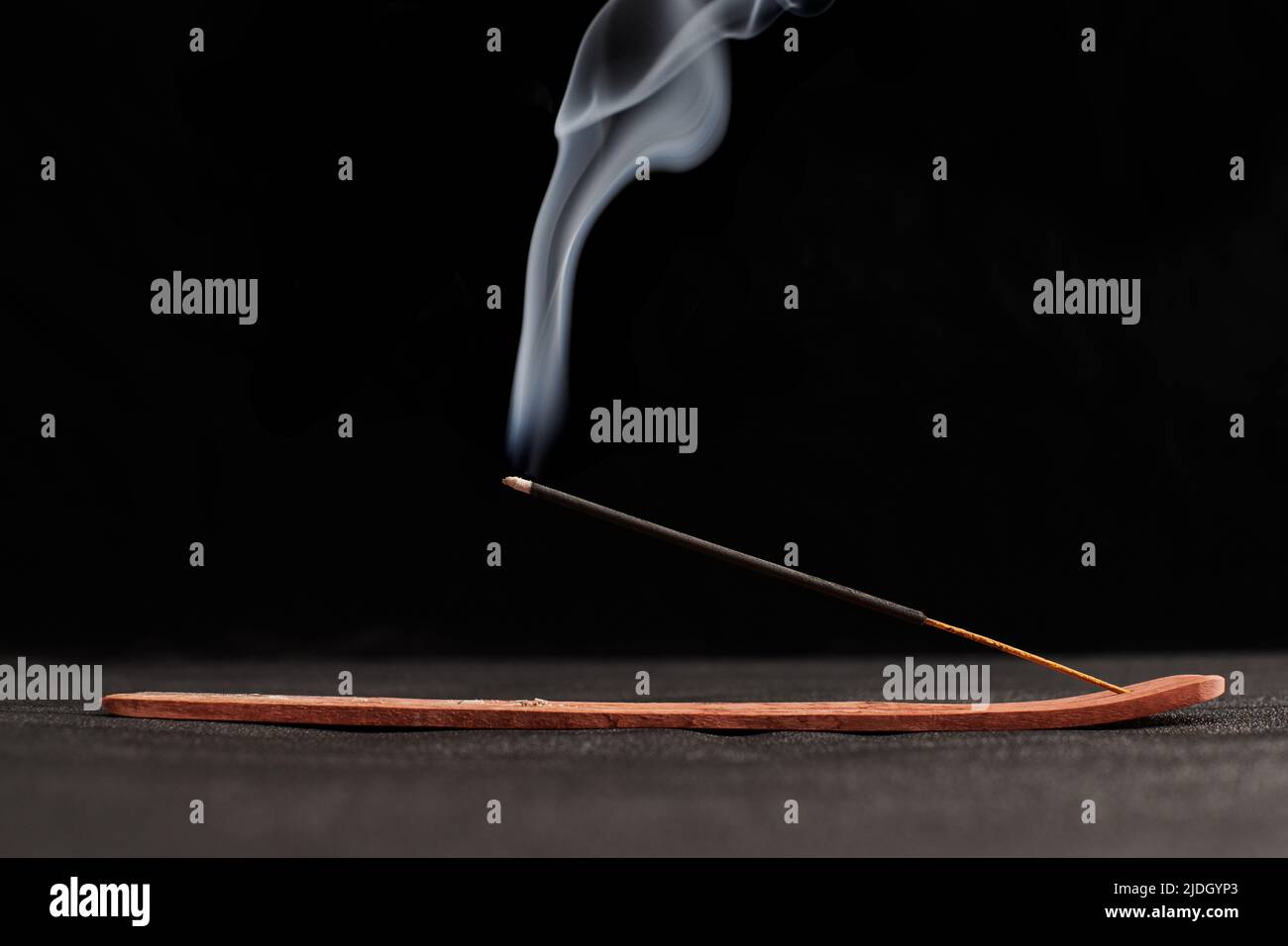 Smoke curls of incense stick in wooden holder for relaxation and ...