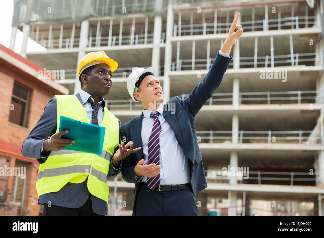 Foreman showing builder something at the construction site by pointing ...