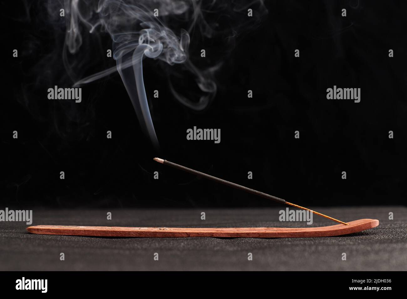 Smoke curls of incense stick in wooden holder for relaxation and ...