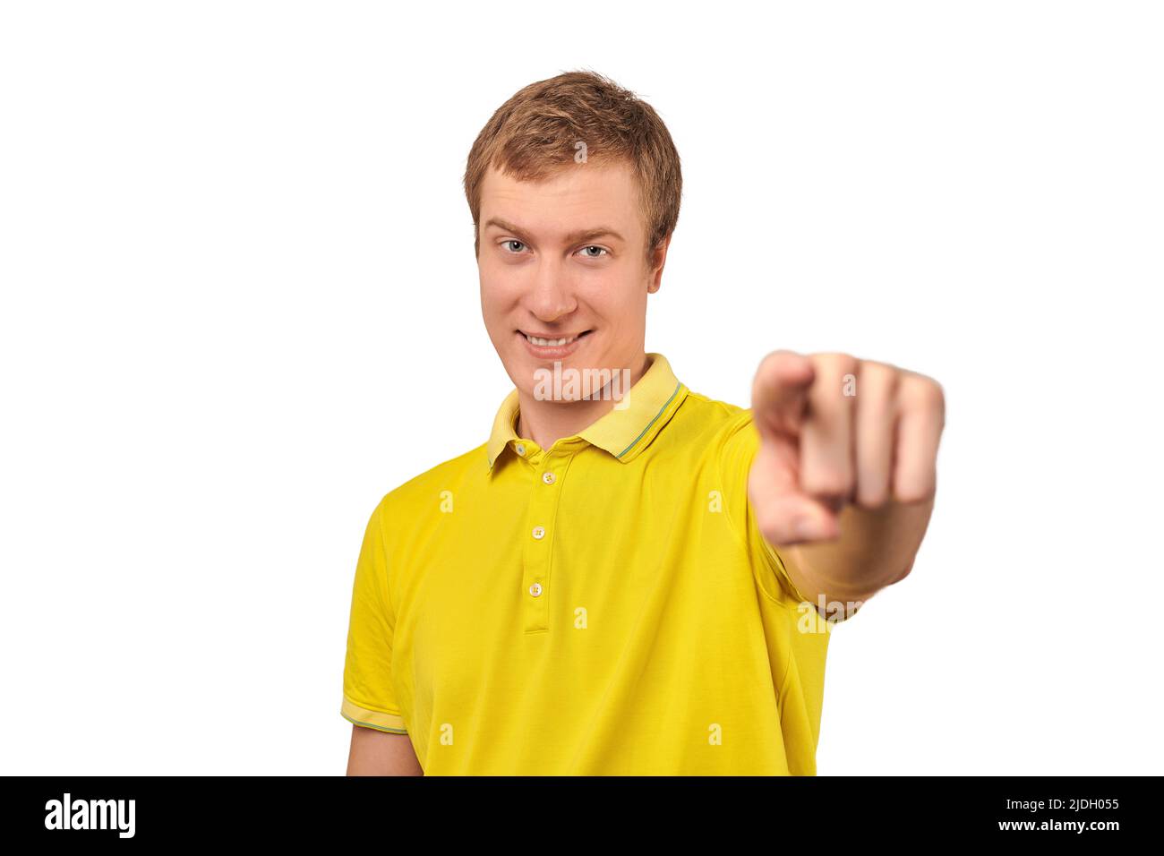 Smiling attractive guy in casual yellow T-shirt pointing finger forward ...