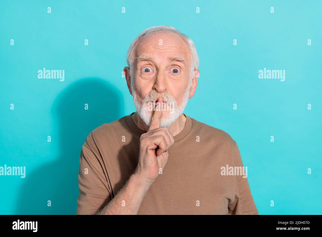 Portrait of attractive mysterious grey-haired man showing shh sign ...