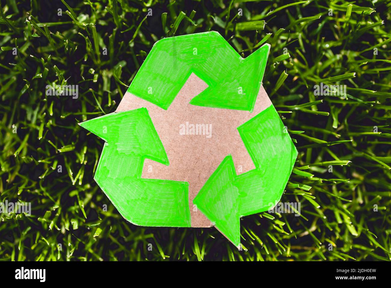 recycle sign hand drawn on cardboard resting on perfect green grass ...