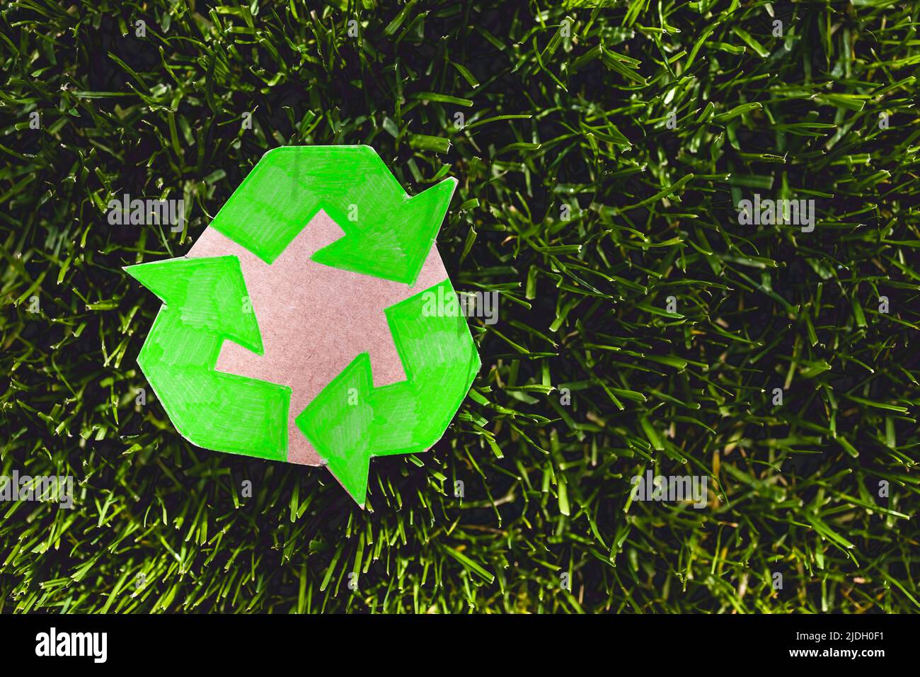 recycle sign hand drawn on cardboard resting on perfect green grass ...