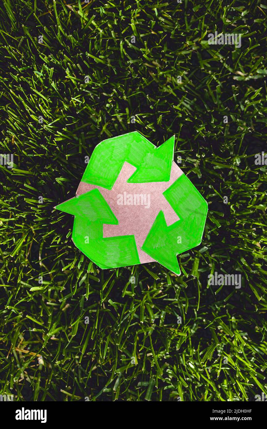 recycle sign hand drawn on cardboard resting on perfect green grass ...