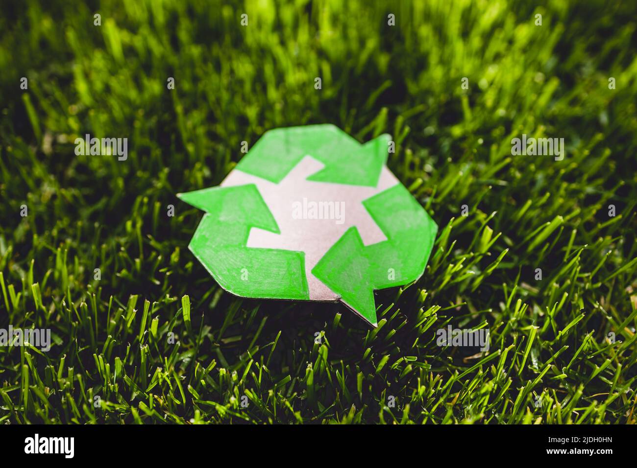 recycle sign hand drawn on cardboard resting on perfect green grass ...