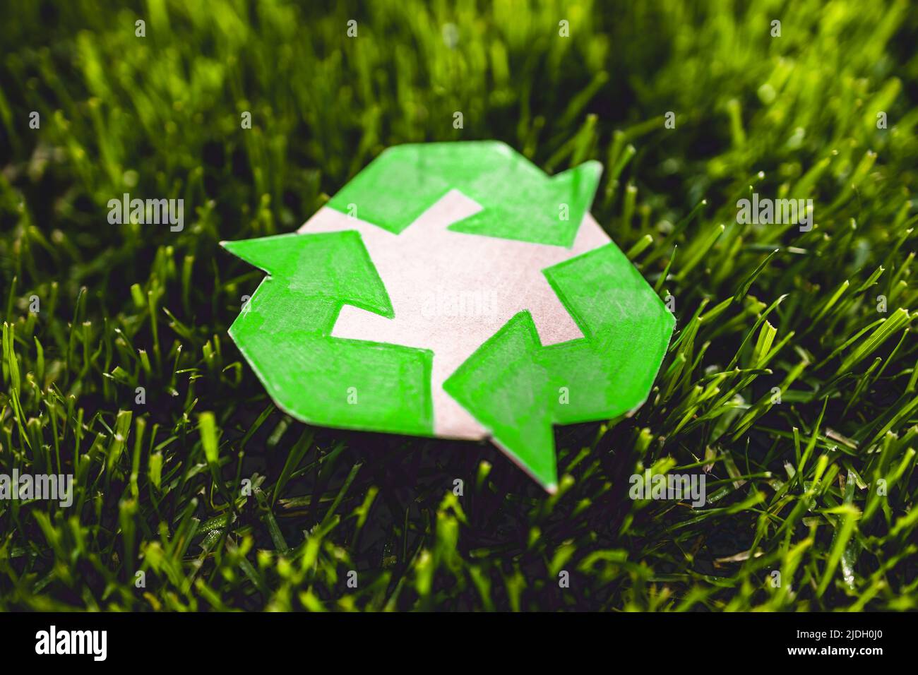recycle sign hand drawn on cardboard resting on perfect green grass ...