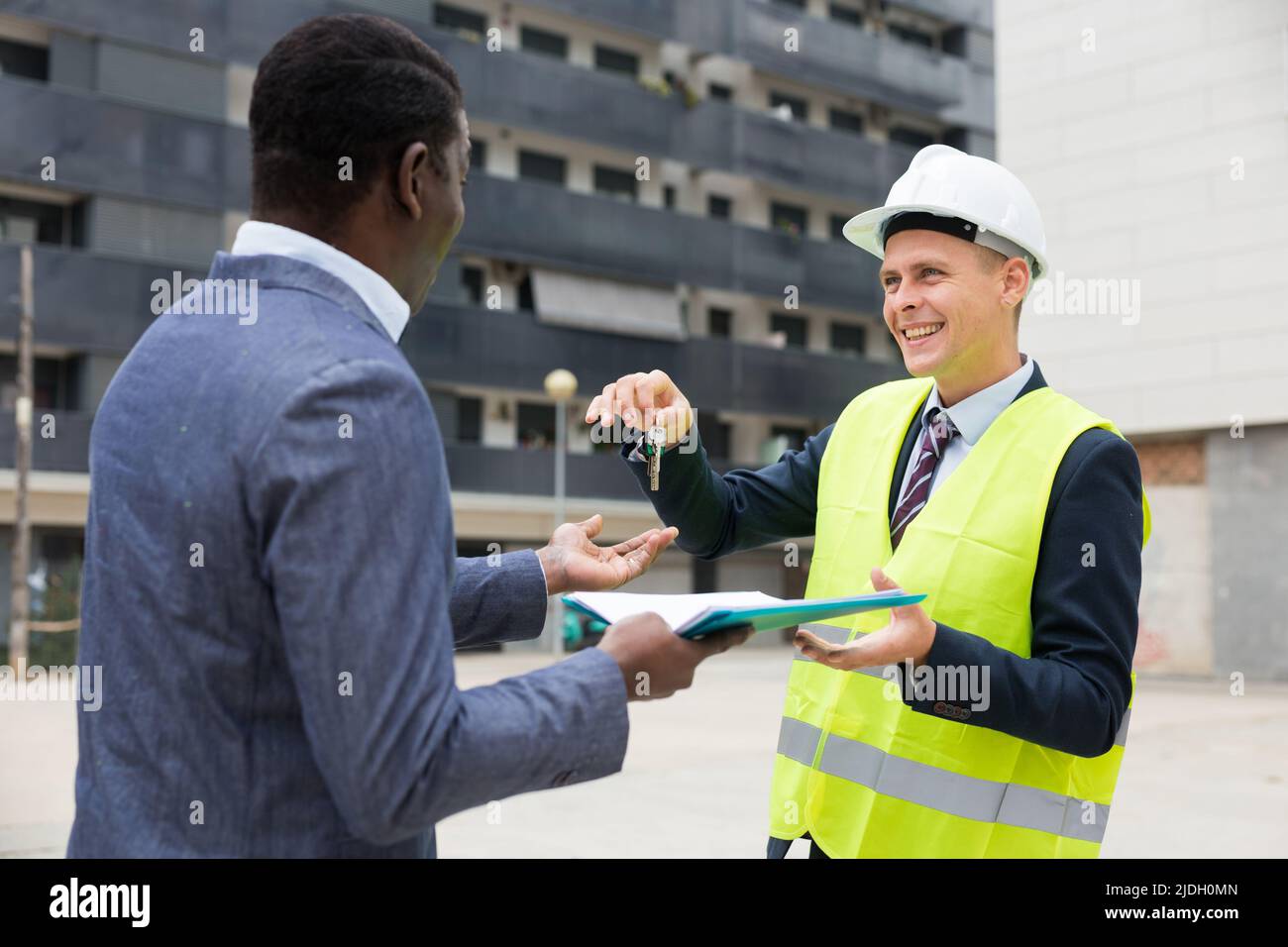 Young smiling contractor hands the keys to a man customer Stock Photo ...