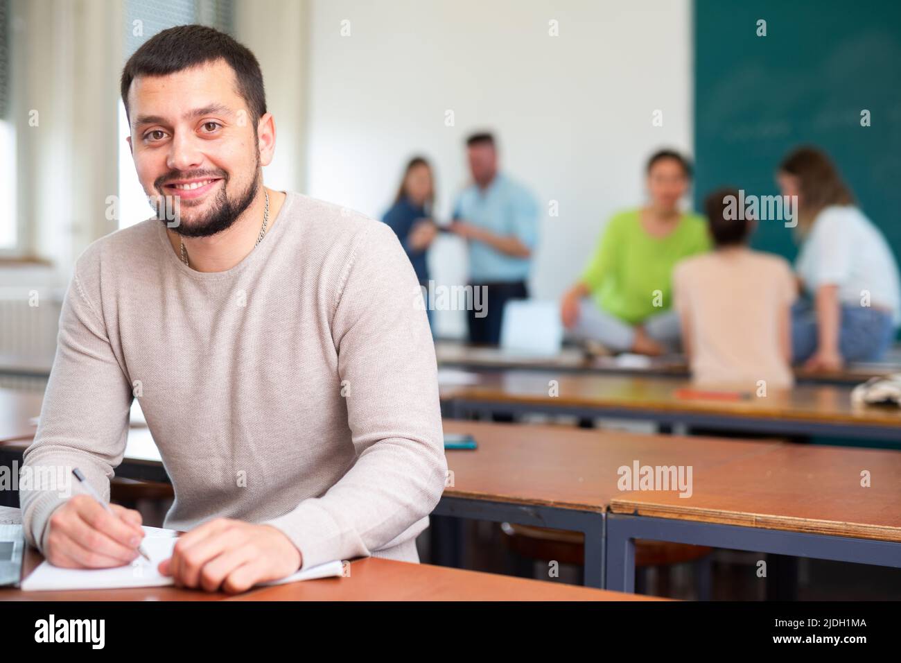 Portrait of positive man student in class room Stock Photo - Alamy