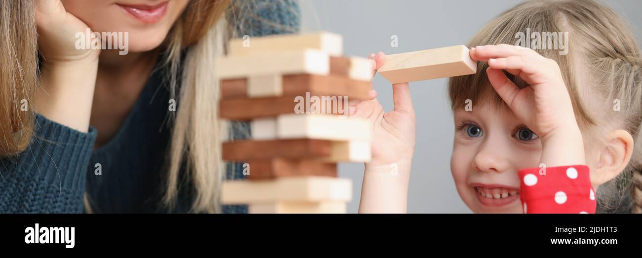 Pretty little kid pulling wooden block out of tower and smile Stock ...