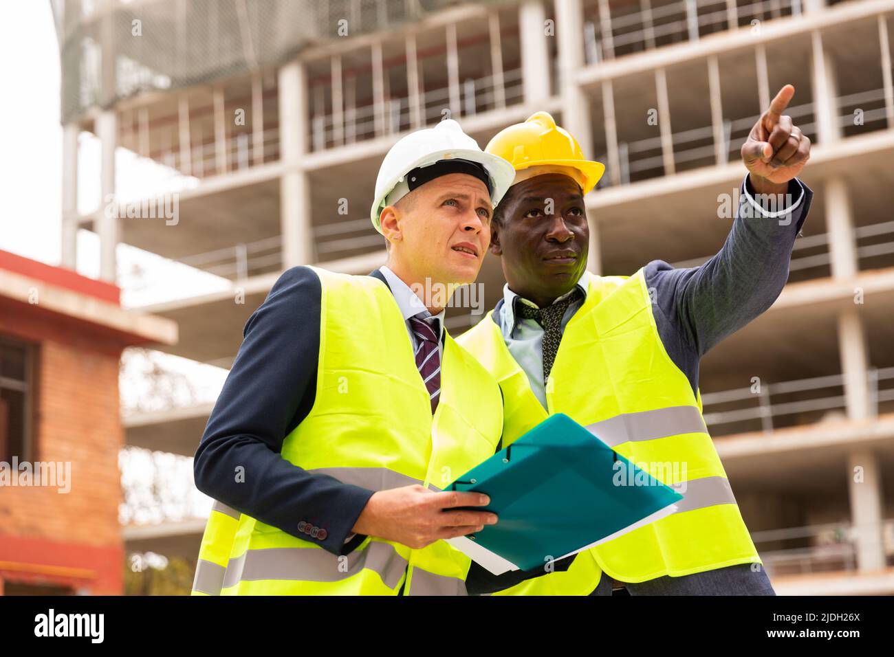 Foreman showing builder something at the construction site by pointing ...