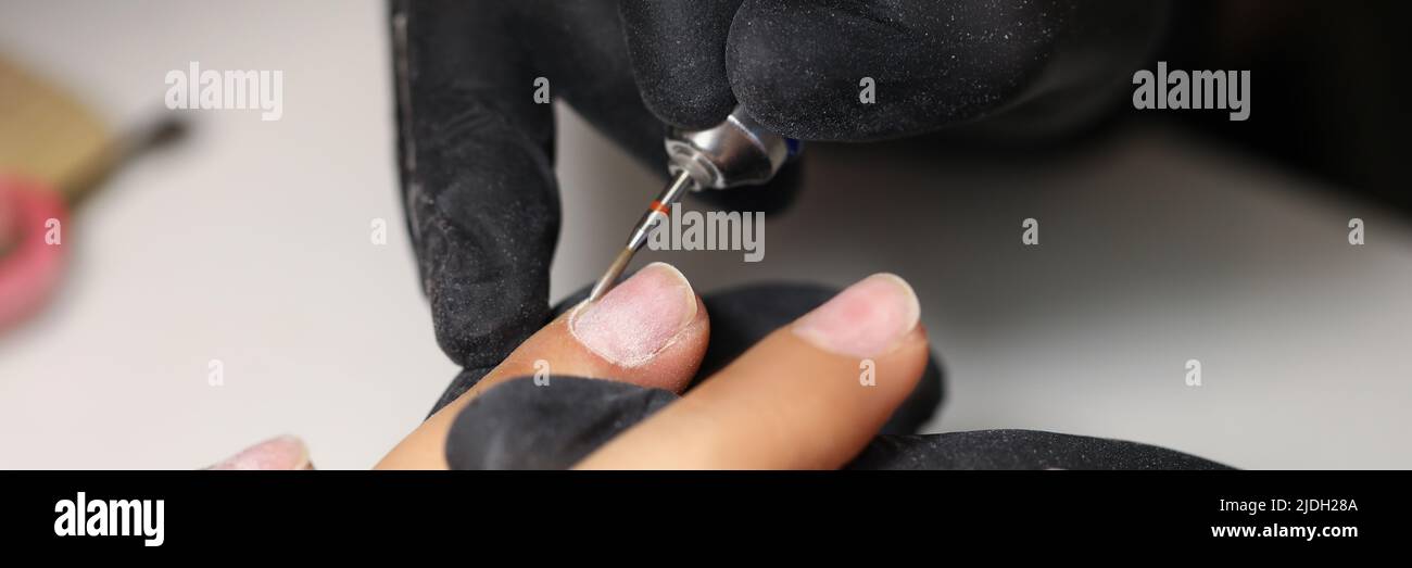 Nail master using tool to clean female clients nails in beauty studio ...