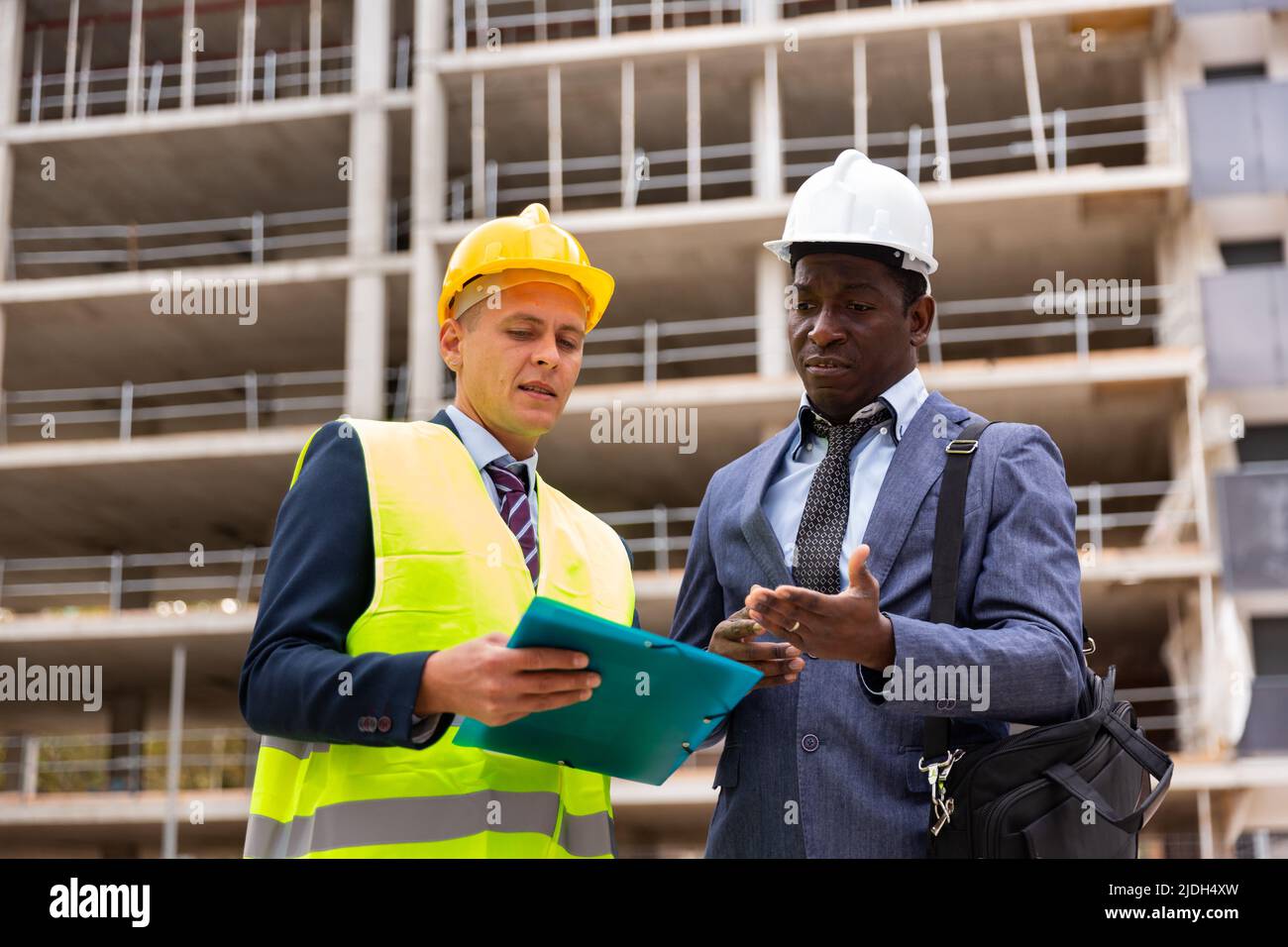 Engineer standing with builder supervising the construction process ...