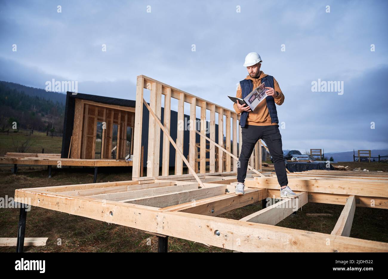 Male carpenter building wooden frame house on pile foundation. Man ...