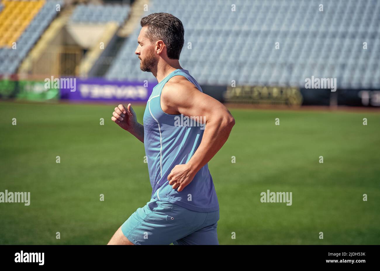 athletic muscular man running in sportswear on stadium track, endurance ...