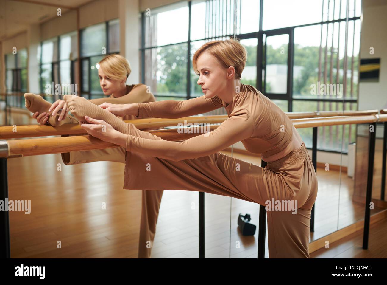 Flexible female dancer stretching legs on ballet barre Stock Photo - Alamy