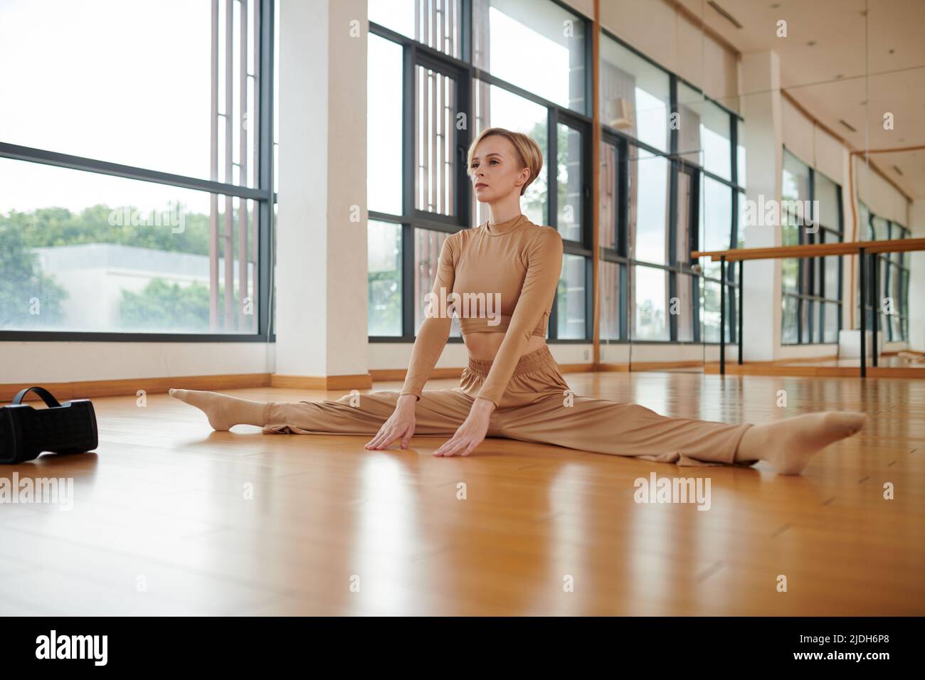 Fit female dancer doing side splits to stretch legs before training ...