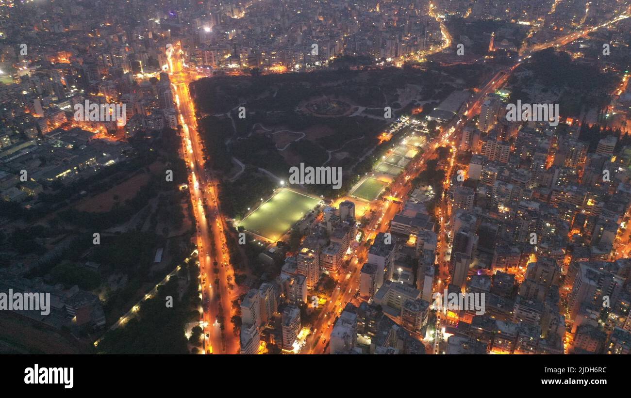 Top aerial night view of a traffic circle and urban park with yellow ...