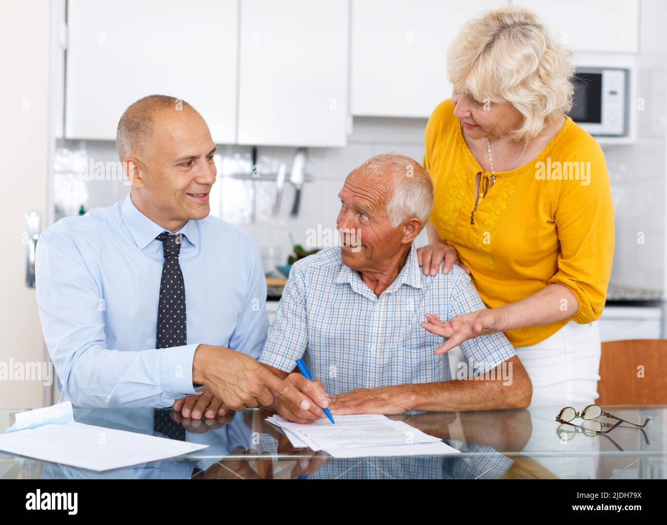 Elderly husband and wife signing agreement papers with bank worker ...