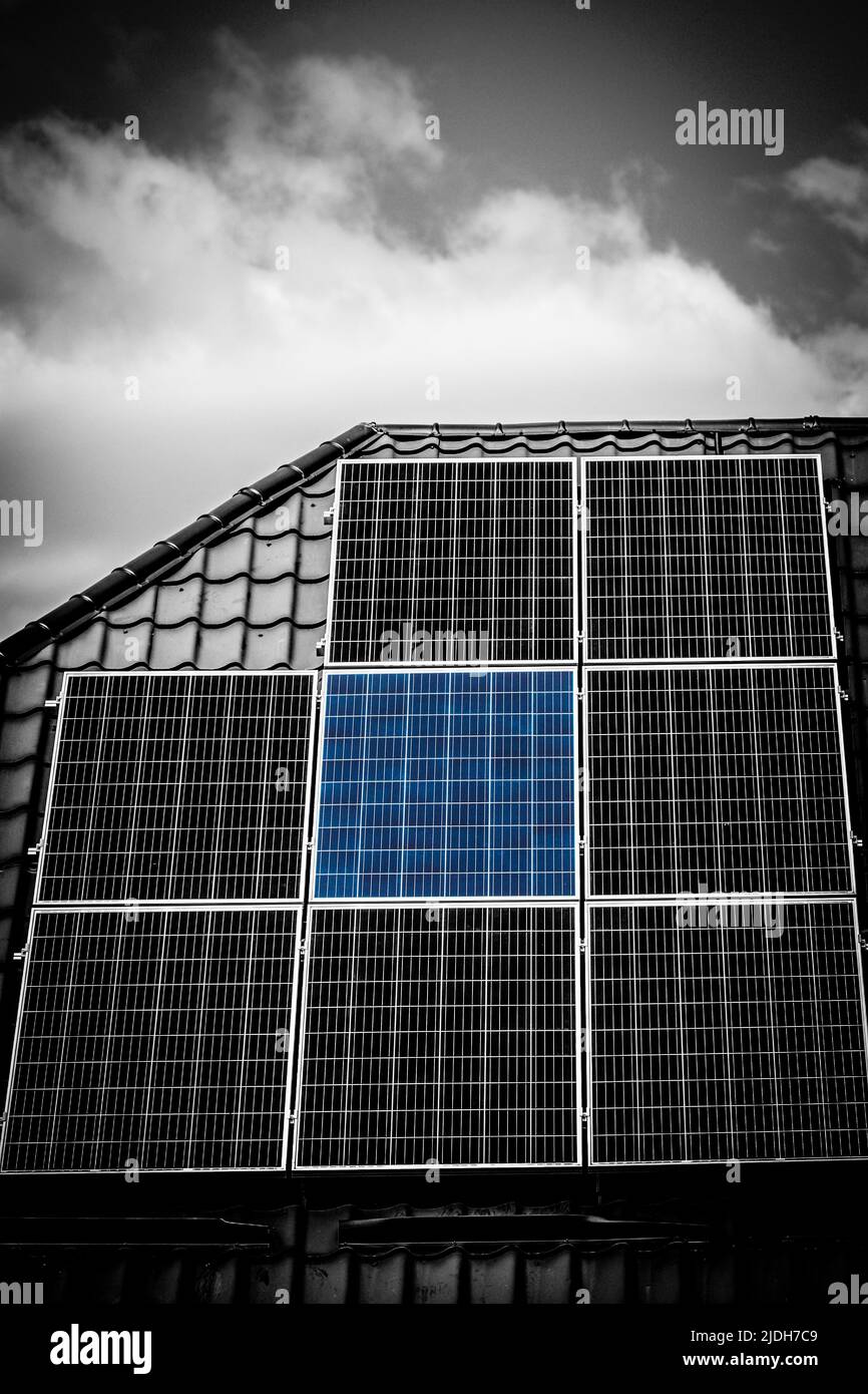 Solar panels mounted on attic roof of house, black and white image with ...