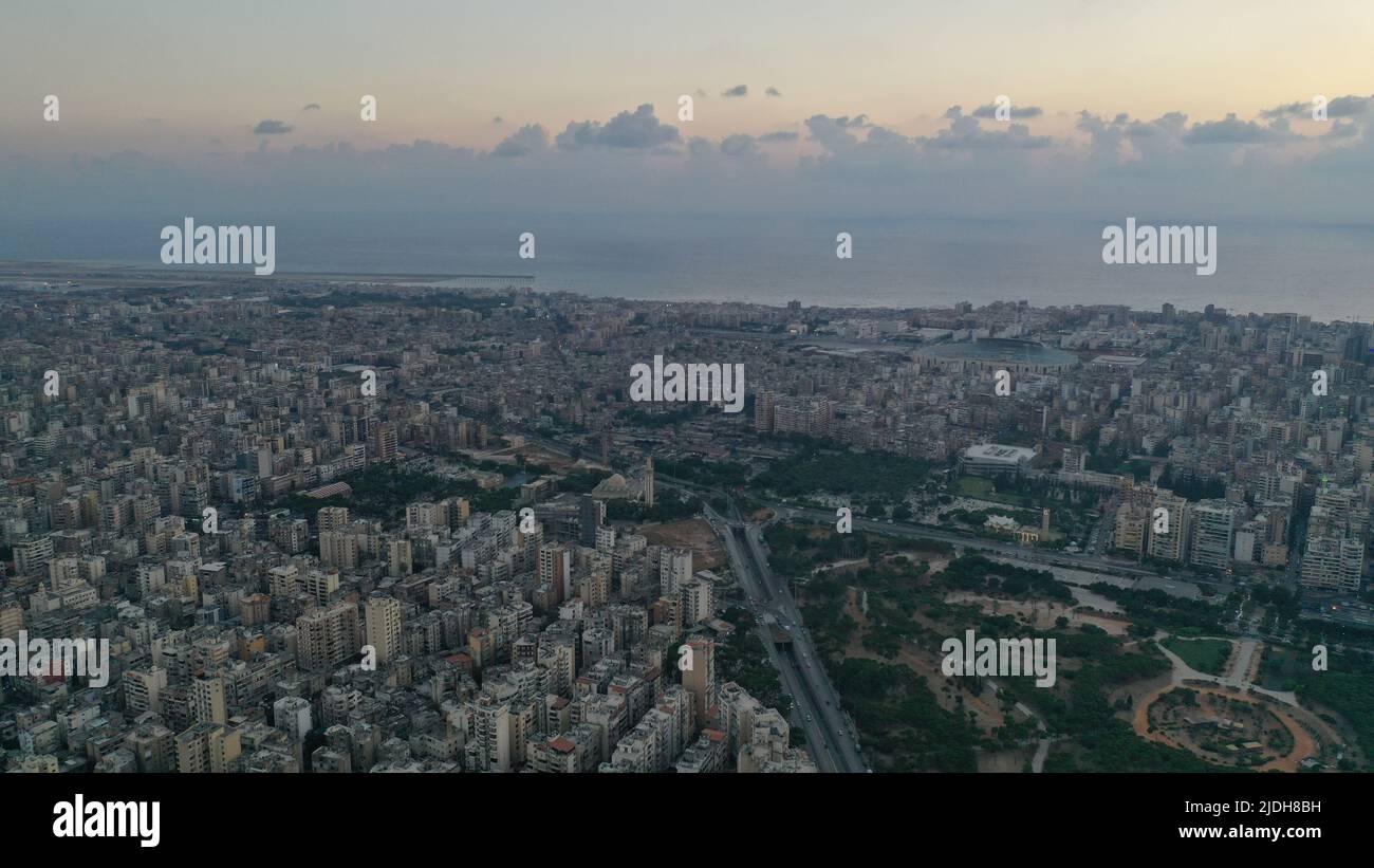 Top aerial view of a traffic circle and urban park with sea background ...