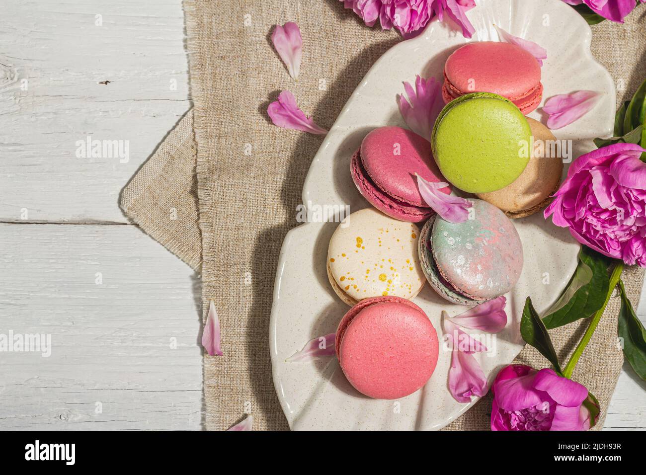 Macarons with a bouquet of peonies on white wooden background. Sweet ...