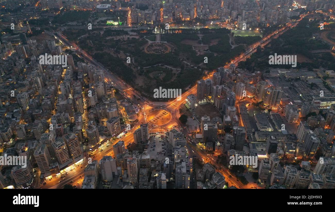 Top aerial night view of a traffic circle and urban park with yellow ...
