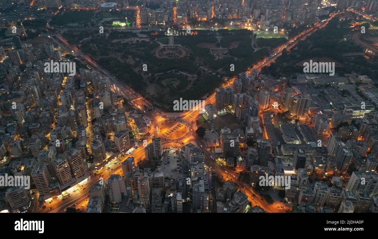 Top aerial night view of a traffic circle and urban park with yellow ...