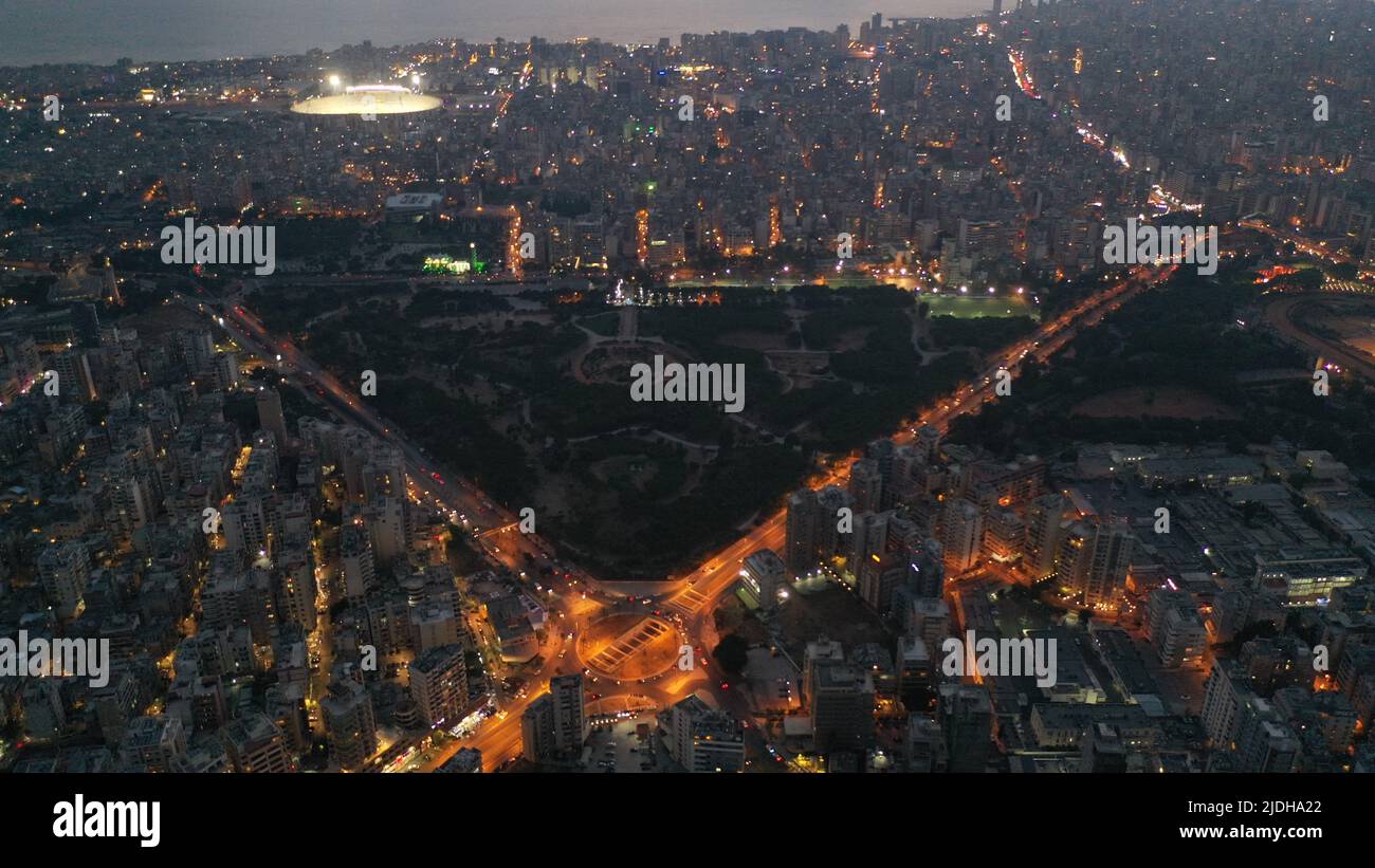 Top aerial night view of a traffic circle and urban park with yellow ...