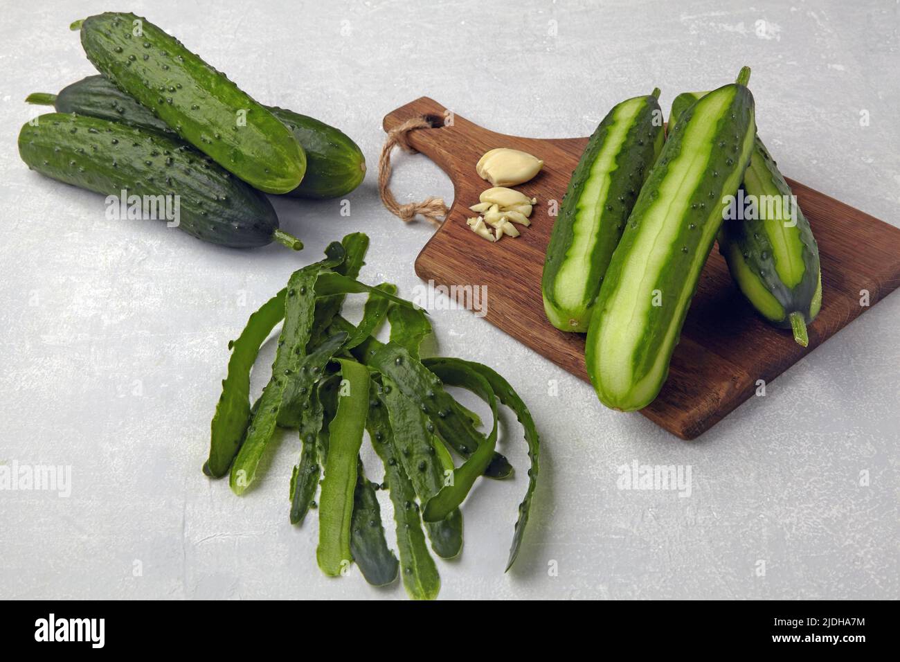 Fresh cucumbers with skin and peeled on a brown wooden cutting board on ...