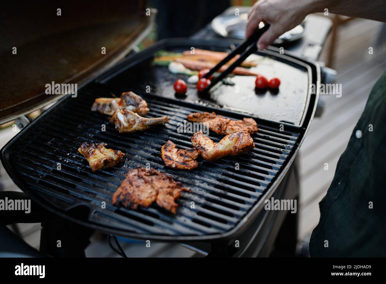 Unrecognizable man grilling meat and vegetable on grill during family ...